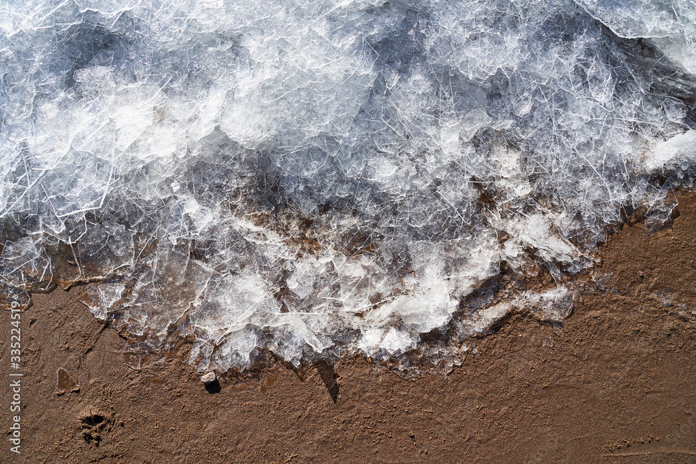 Ice on beach. Border of winter and summer. Ice and sand. Cold and warm ...