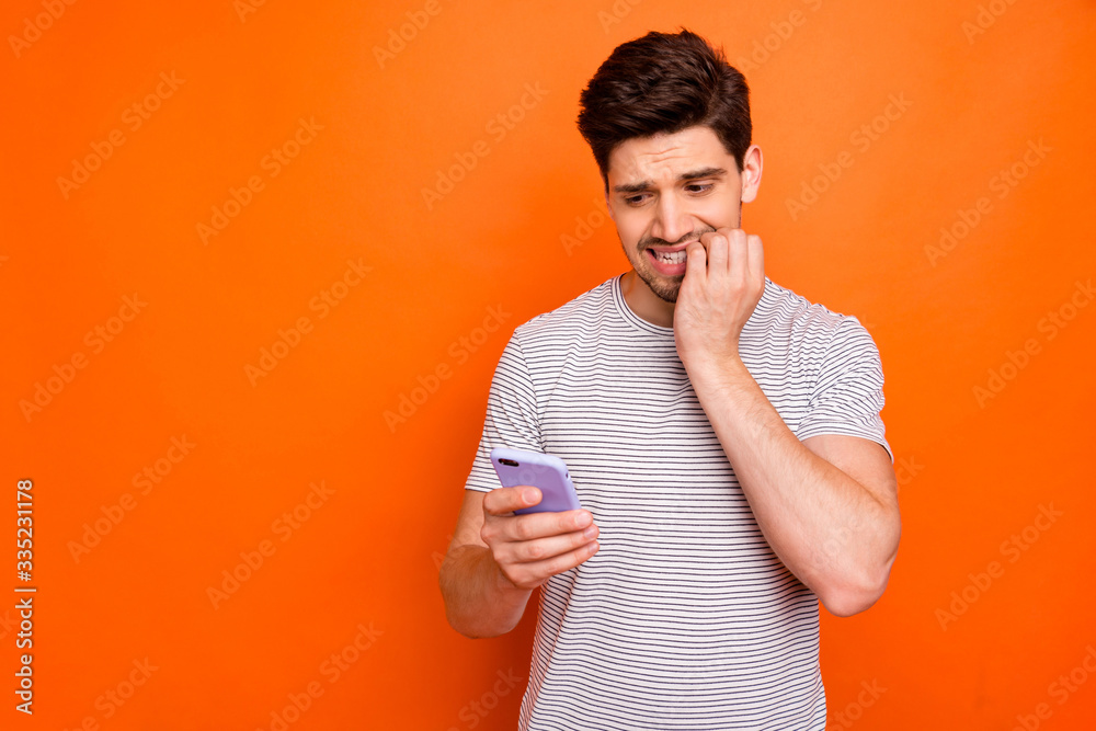 Oh no. Photo of terrified millennial guy hold telephone hand biting ...