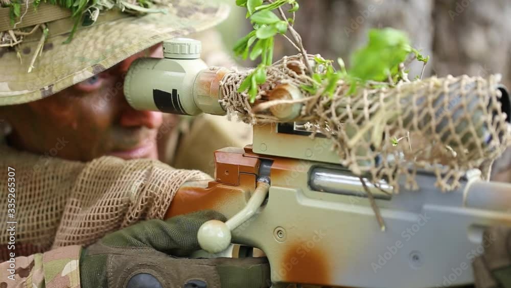 Close-up. Looking through the sniper scope and reloads rifle. Ghillie ...