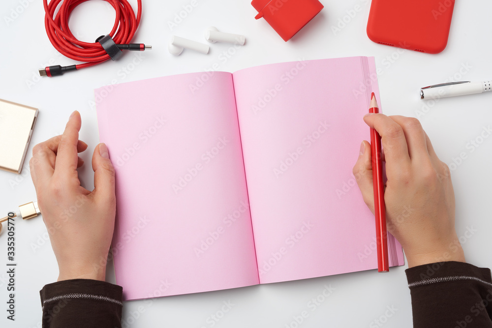 open notebook with blank pink pages and two hands, concept of writing a ...