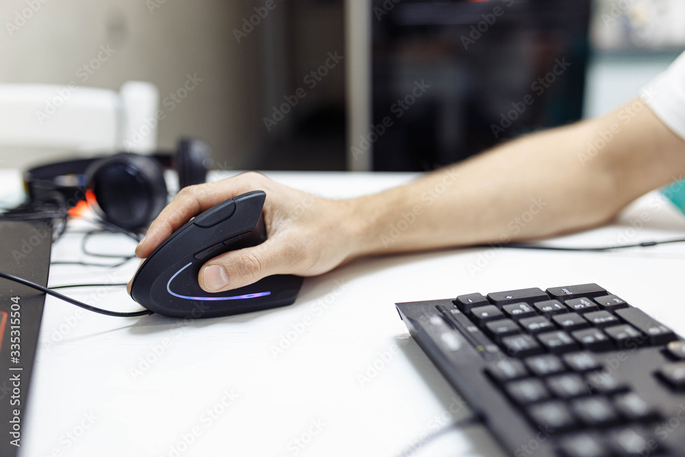 In the man’s hand, a vertical ergonomic computer mouse-joystick is used ...