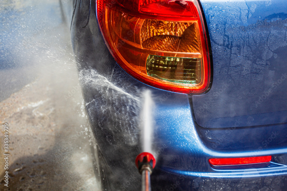 Close-up man holding high-pressure water sprayer for car rear stop ...