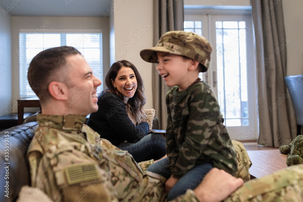 Happy military family laughing on living room sofa Stock Photo | Adobe ...