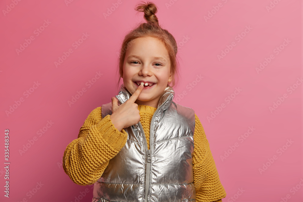 Cute small ginger girl indicates at her new adult tooth, has combed ...