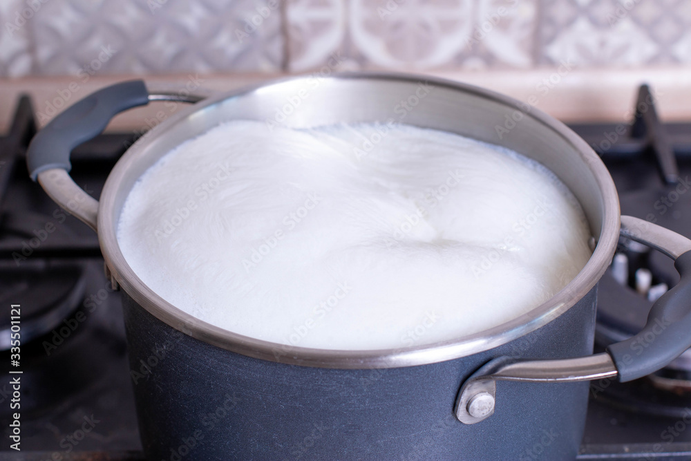 Milk boiling over a pan Stock Photo | Adobe Stock