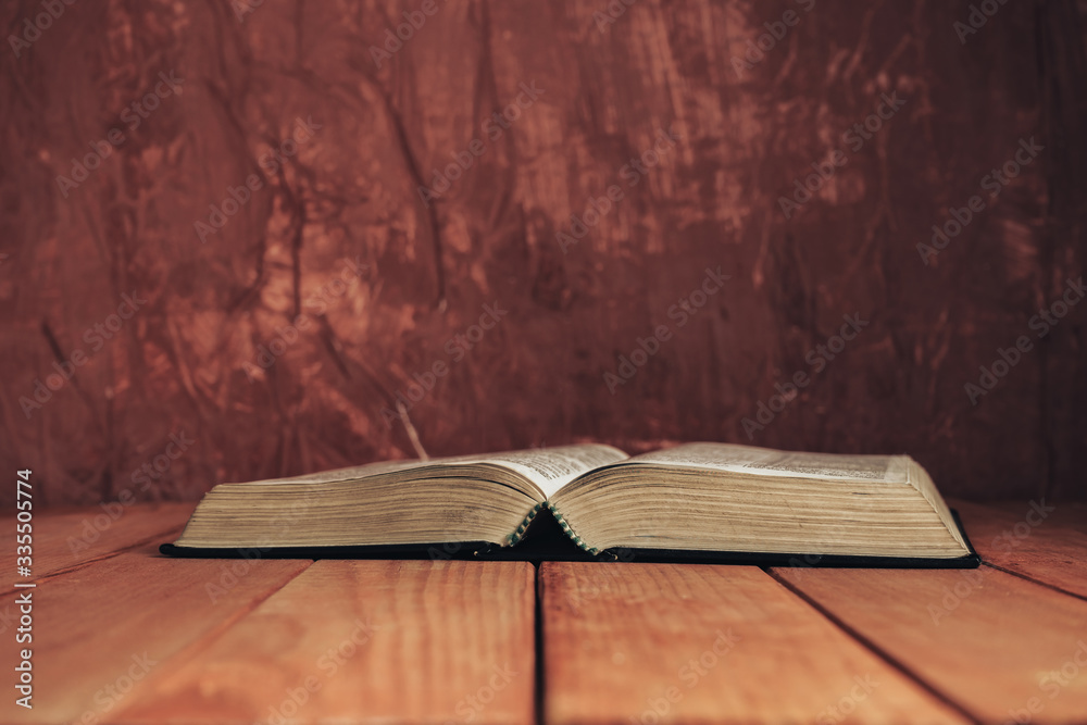 Open bible on a red old wooden table. Beautiful brown wall background ...