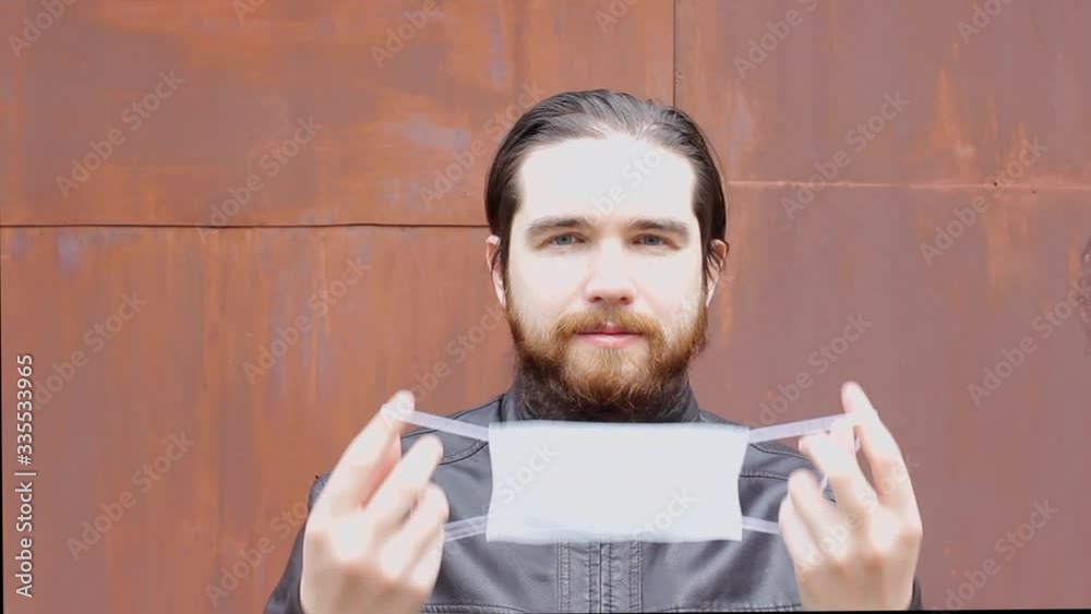 man puts on and removes a disposable mask to protect against the ...