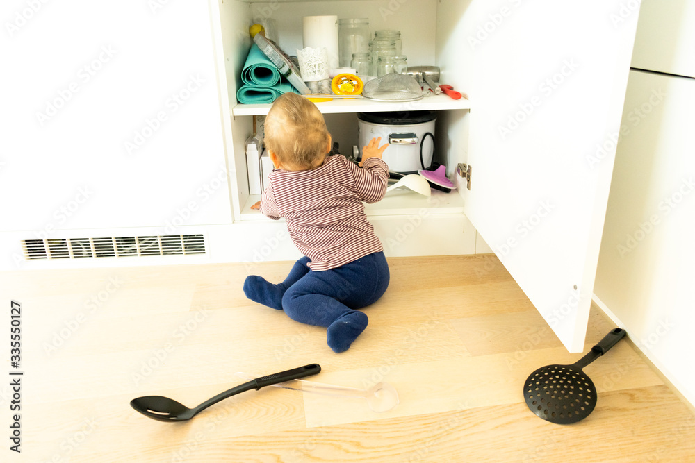 Toddler making mess in kitchen. Infant plays and discovers kitchen ...