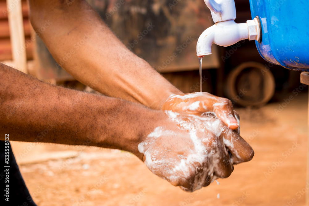 young black person washing her hands with soap under a tap of water ...