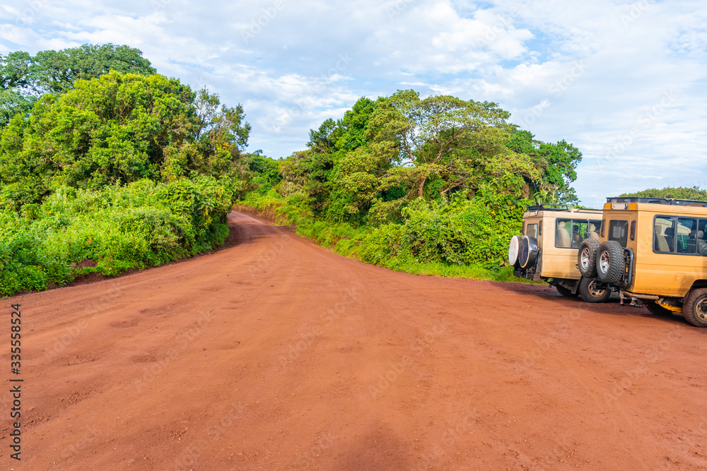 Safari jeep driving on busy dirt road on floor of Ngorongoro Crater ...