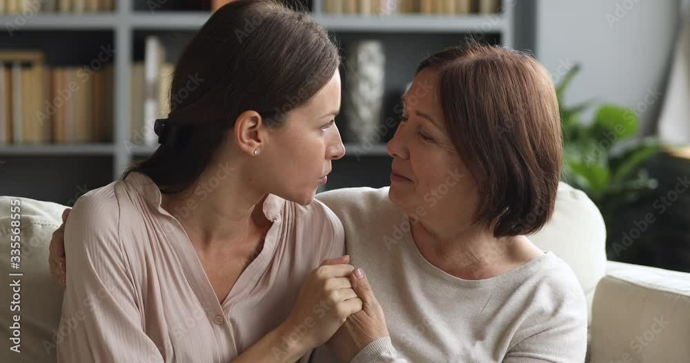 Affectionate middle aged woman embracing holding hands of grown up ...