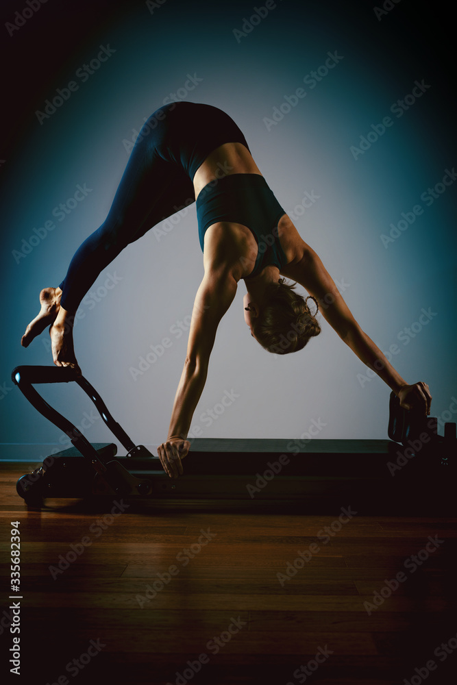 Young girl doing pilates exercises with a reformer bed. Beautiful slim ...