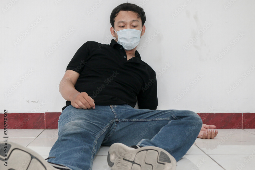 Sick asian man flu is sitting on ground at home with using mask ...