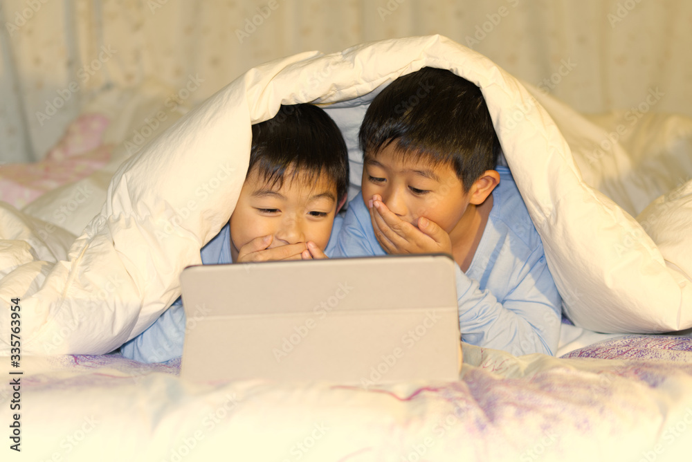 Two boys wearing pajamas are watchinging digital tablet screen for ...