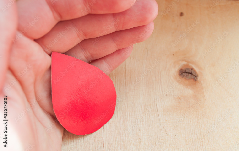World Blood Donor Day. World Hemophilia Day. Hand holds a drop of blood ...