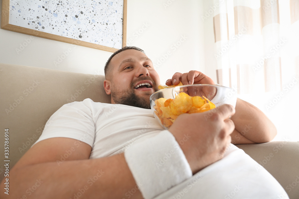 Lazy overweight man eating chips at home Stock Photo | Adobe Stock