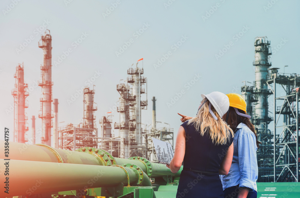 Two woman worker in oil refinery plant with computer in hand and lady ...
