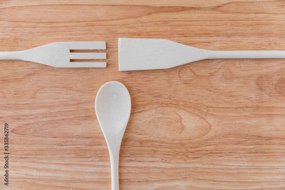 A white wooden spoon, a spatula and a spatula with cloves lie opposite ...
