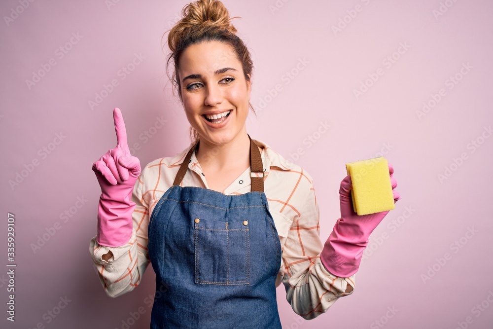 Beautiful blonde cleaner woman doing housework wearing arpon and gloves ...
