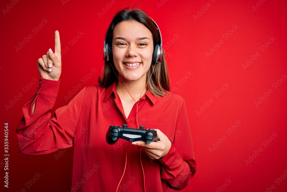 Young beautiful brunette gamer girl playing video game using joystick ...