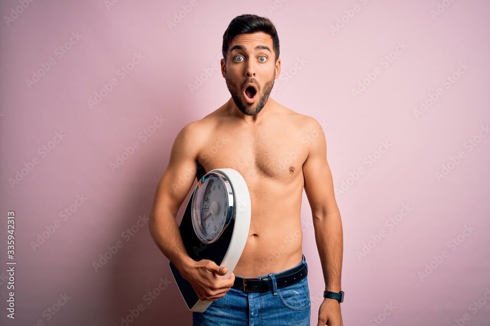 Young handsome slim man with beard shirtless holding weight machine ...