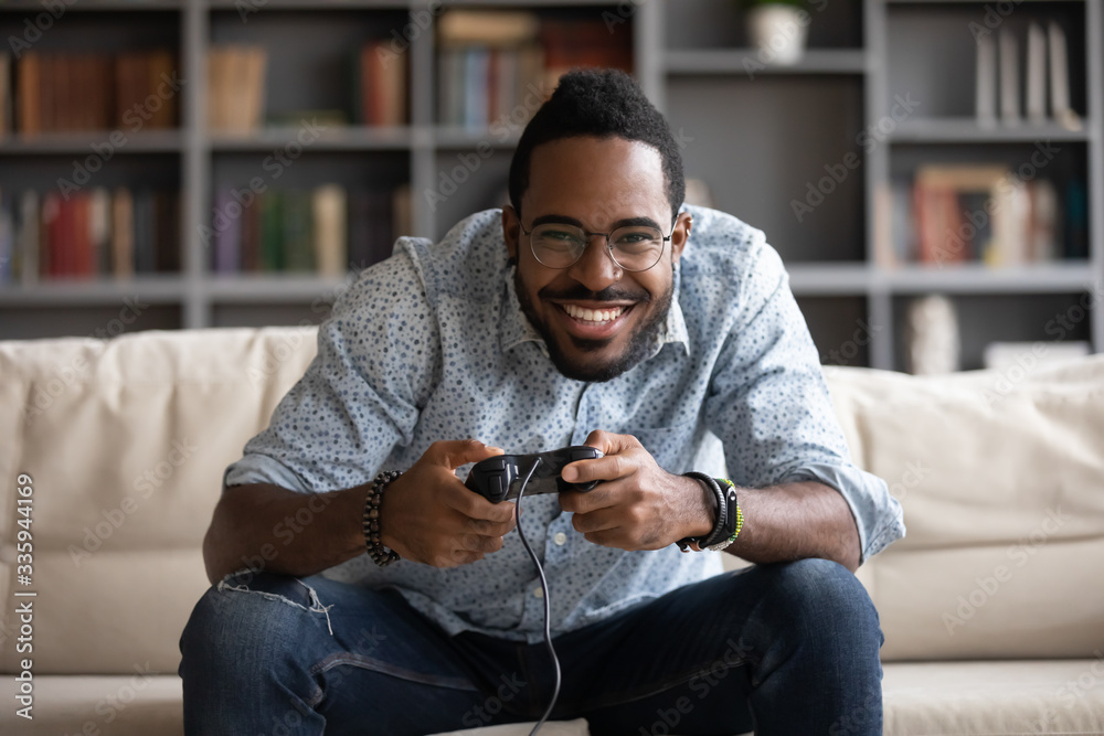 Overjoyed African American millennial man relax on couch in living room ...