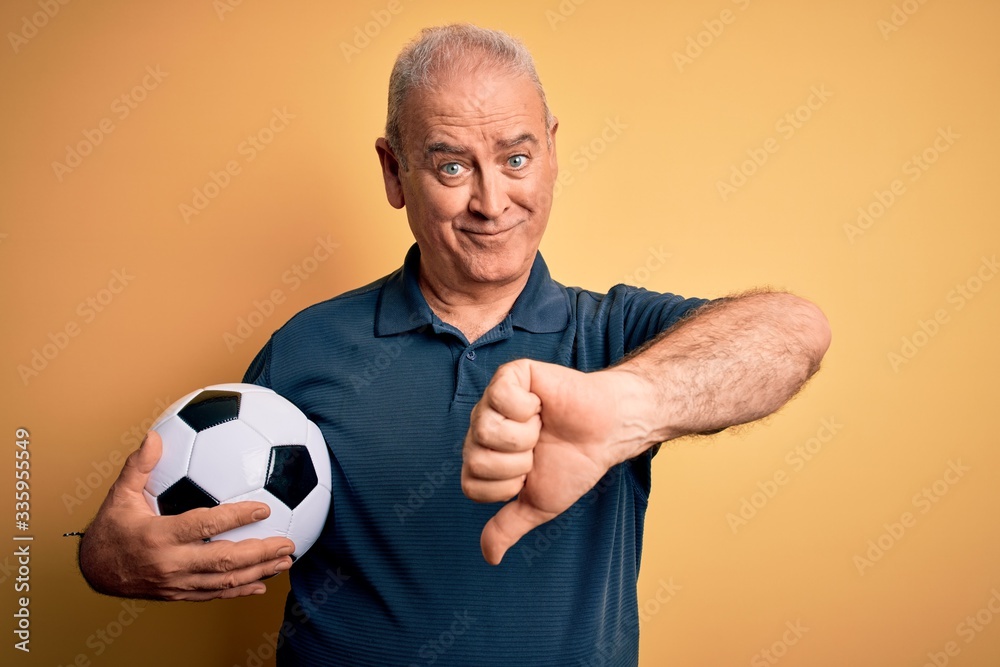Middle age hoary player man playing soccer holding football ball over ...
