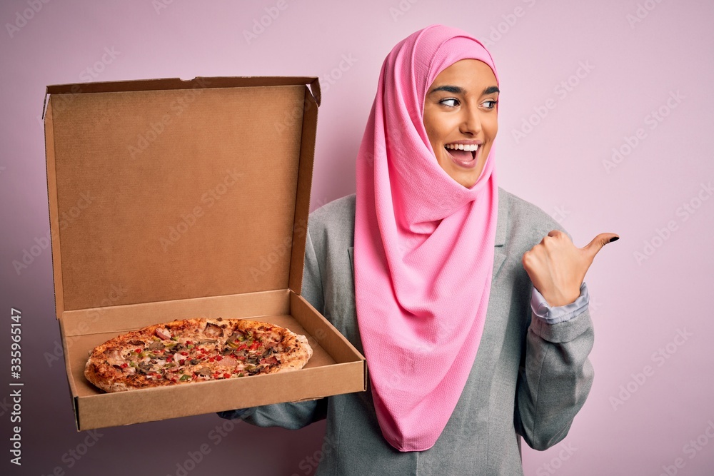 Young beautiful arab woman wearing pink muslim hijab holding delivery ...