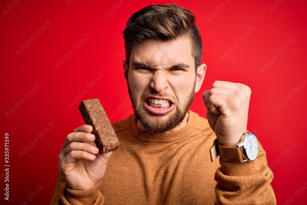 Young blond man with beard and blue eyes eating healthy chocolate ...
