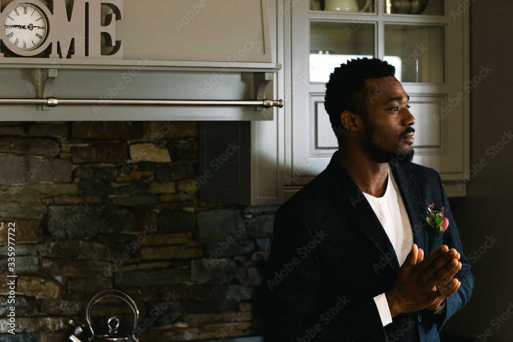 guy in a handsome jacket in the kitchen. African American groom in the ...
