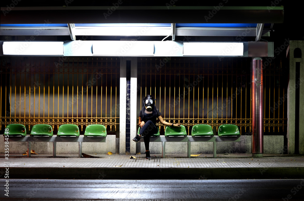 balck dress women in full mask sitting alone at bus stop in night life ...