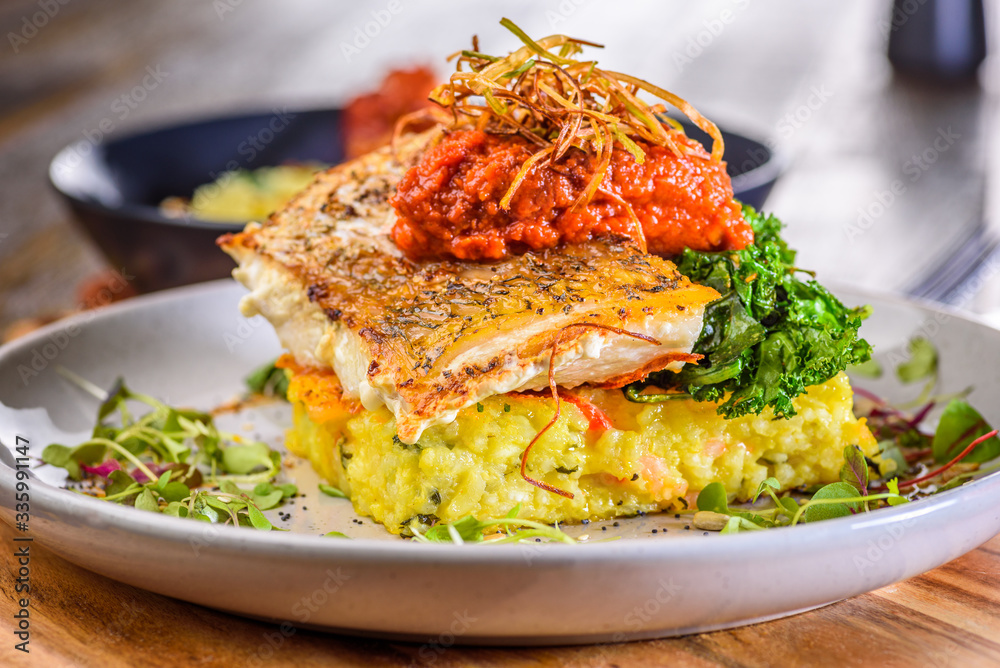 A serving of Fish of The Day, Snapper with Crispy Paella Cake, Wilted ...