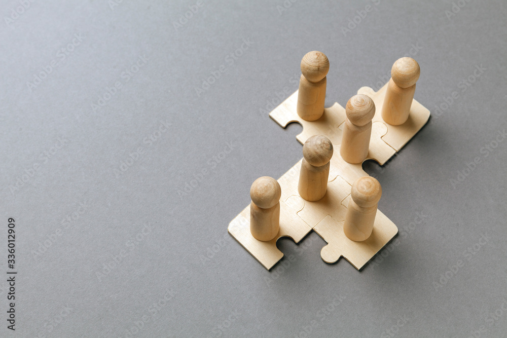 Wooden figures on puzzles on grey background as a symbol of team ...