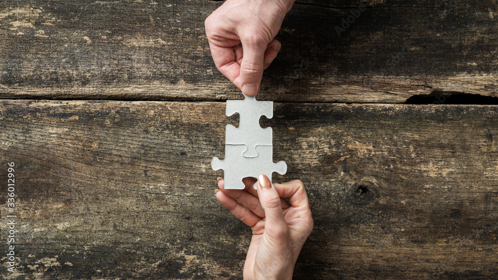 Photo & Art Print Male and female hands joining two matching puzzle ...