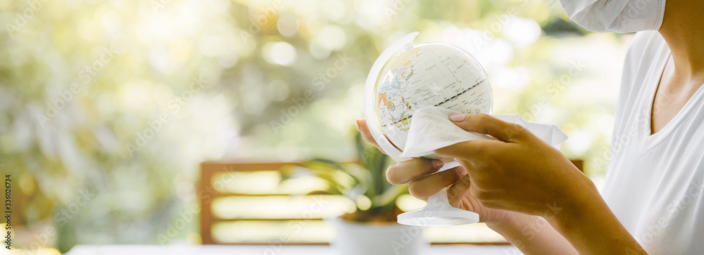 Asian woman cleaning globe with disinfection wipe with garden in ...