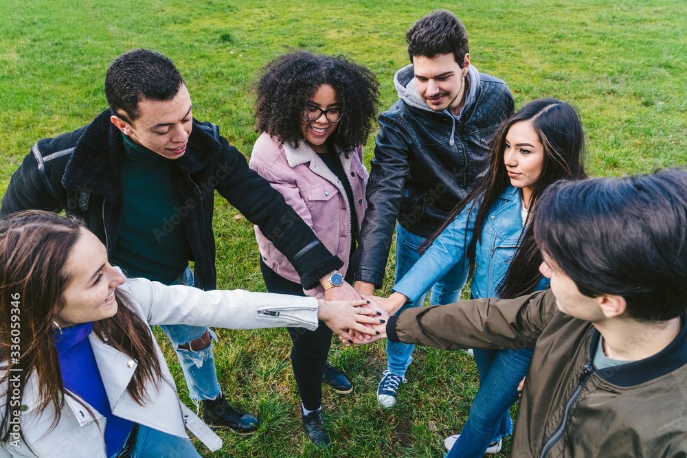 Group of young friends at the park join hands in the center of a circle ...