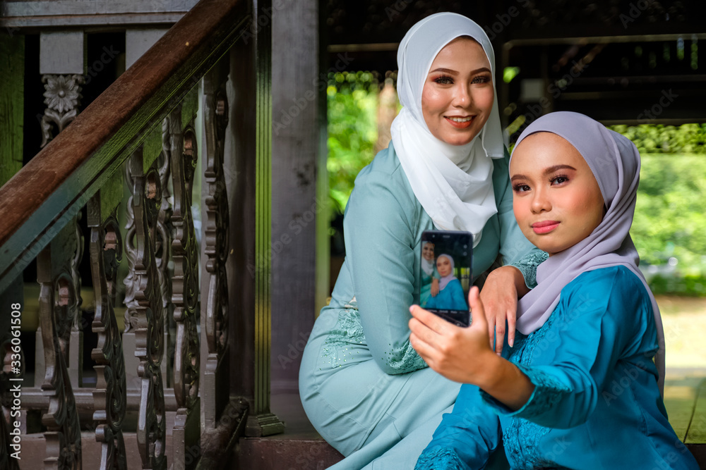 Muslim Malay women wearing hijab and traditional costume are taking ...