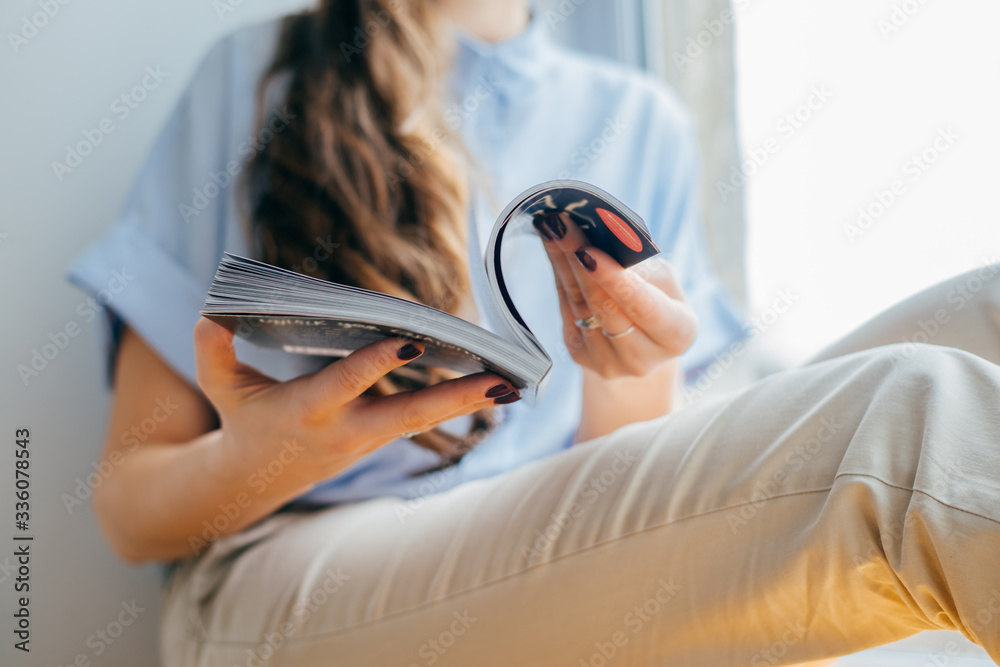 Attractive girl reading magazine on window. girl holding magazine at ...