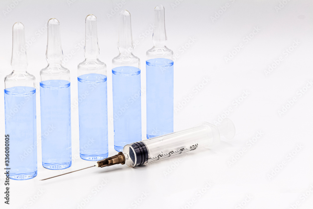 Five glass vials of the vaccine, blue in color, and a syringe on a ...