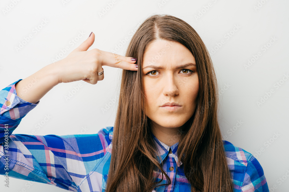 Blonde, young woman pulling a gun gesture at her head.isolated on white ...