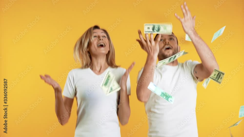 Surprised happy couple enjoying money rain banknotes falling down ...