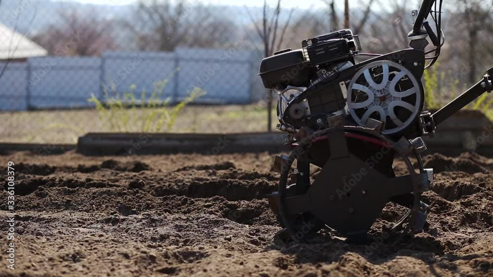 Gardener man cultivate ground soil with tiller tractor or rototiller ...