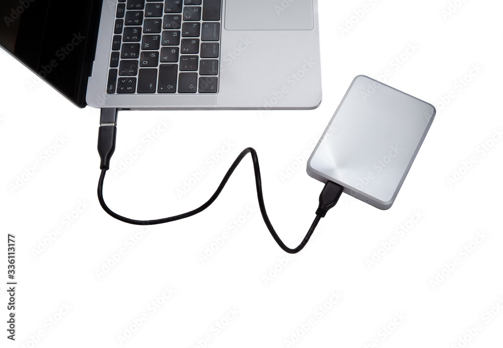Silver external hard disk drive connected to a laptop computer for data ...