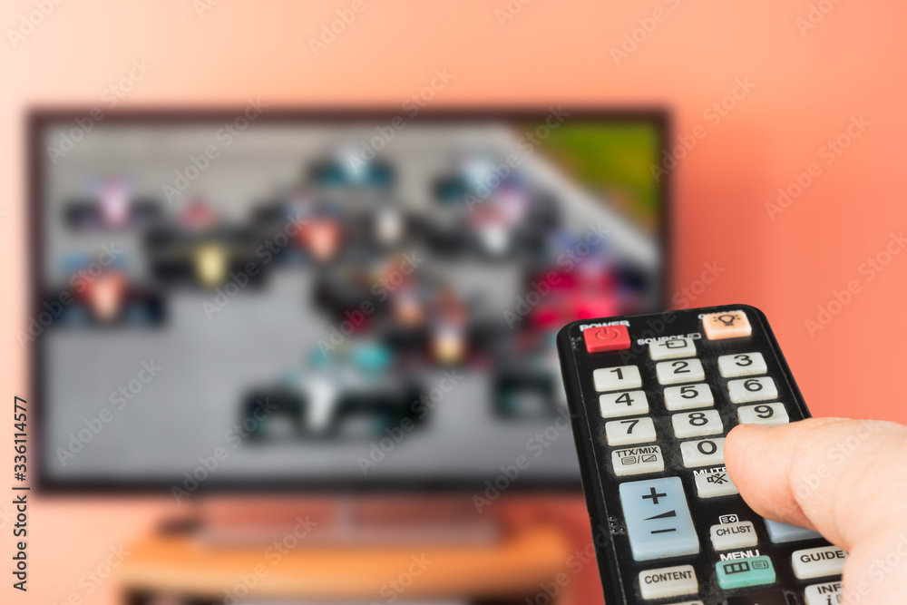 Caucasian man watching formula 1 race on TV at home. Changing channels ...