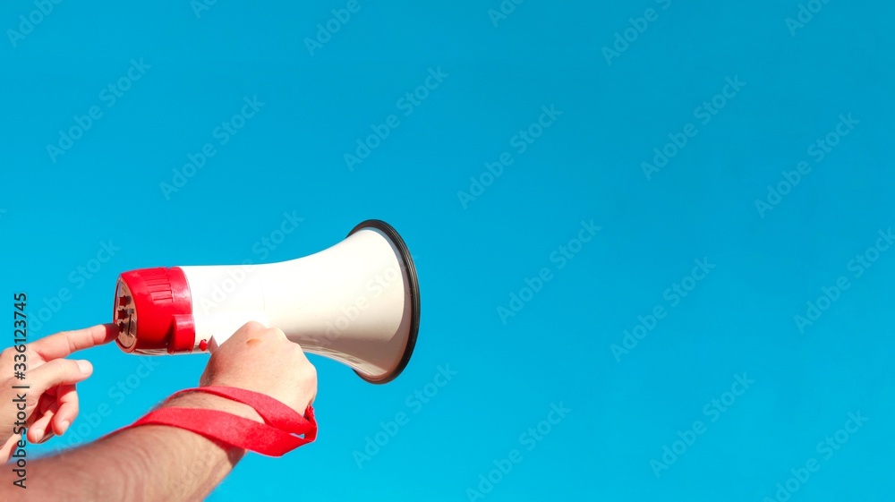 Imagen de una mano humano sujetando un megafono con fondo azul del ...