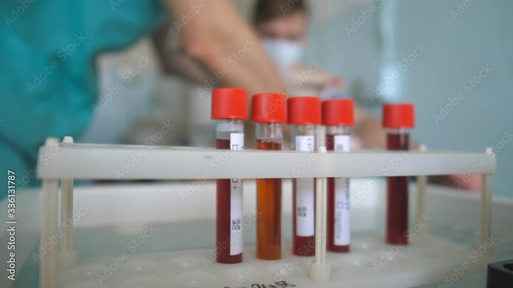 Doctor takes a blood sample from a patient and adding test tube in rack ...