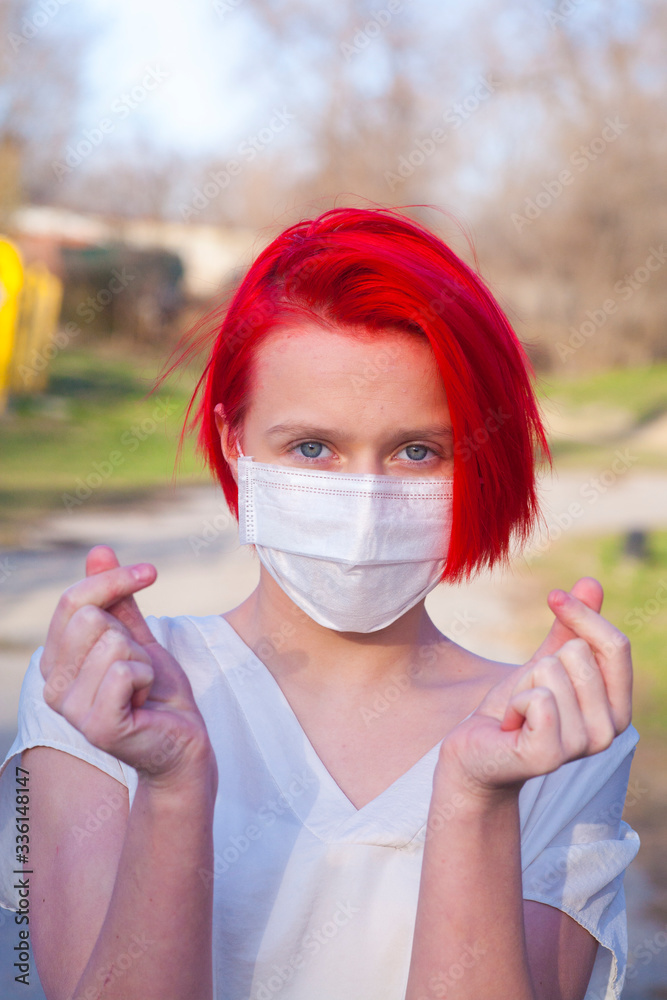 Red hair teenage girl wearing a medical mask shows the Korean two ...