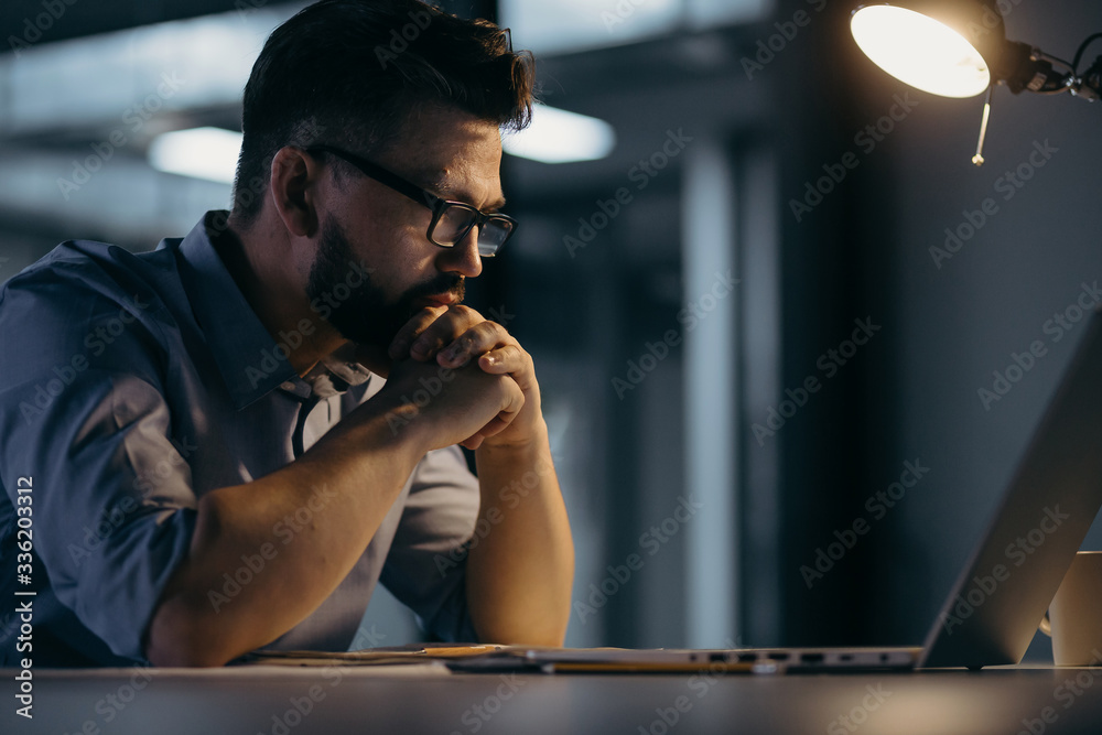 Man works at night office alone and thinking about his problems or job ...