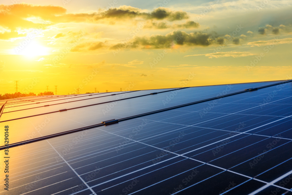 Photovoltaic solar panels and high voltage power lines at sunset sky ...
