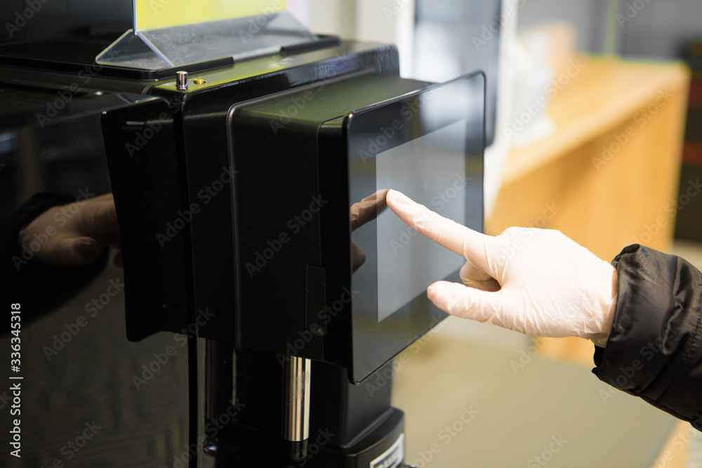 hand in a white glove touches the screen on a vending machine in a ...